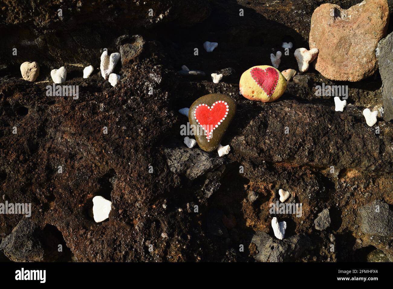 Heart shaped coral and stones, painted with bright red "love" hearts ...