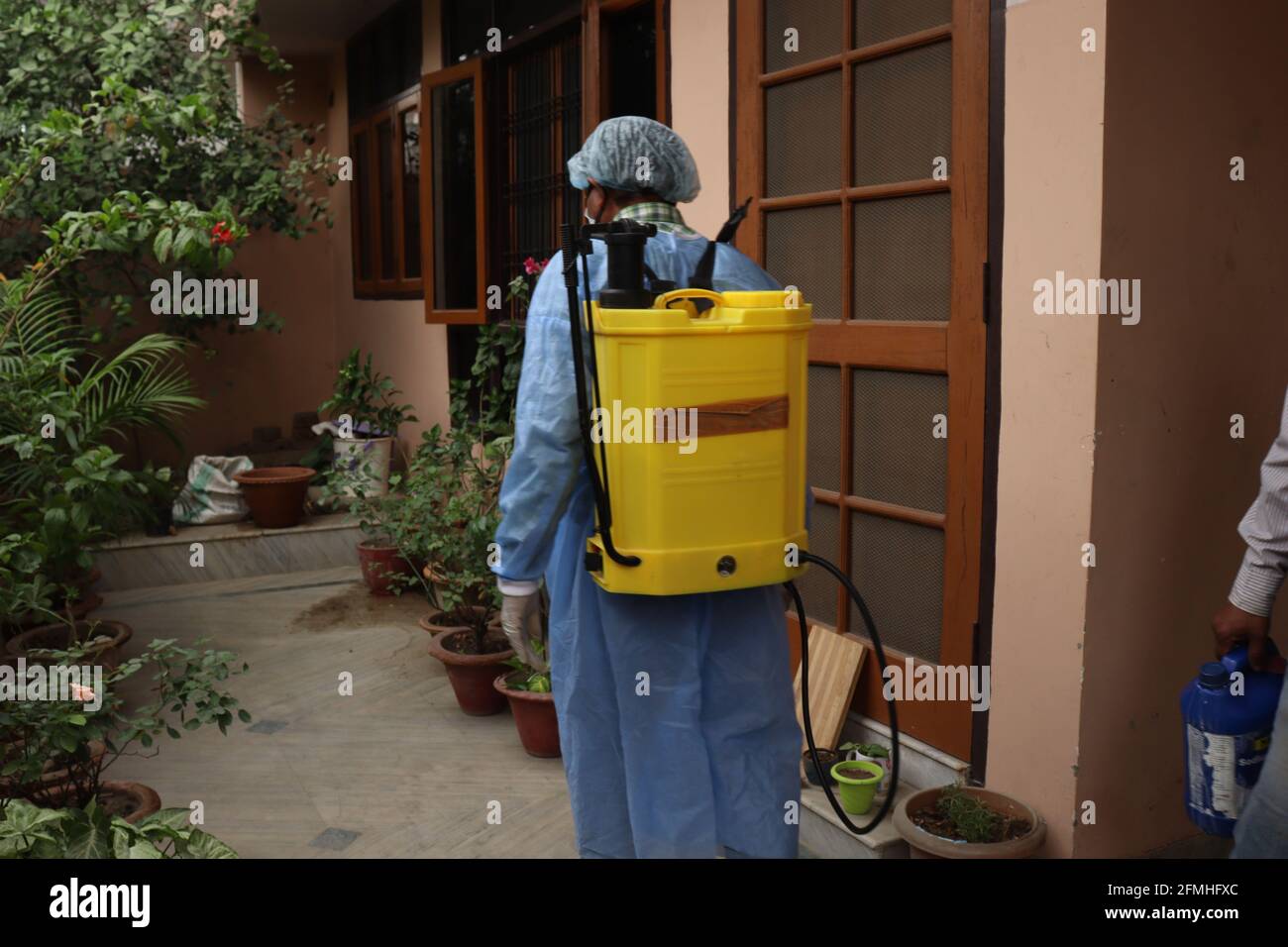 A professional worker in PPE uniform using sanitizing spray Stock Photo ...