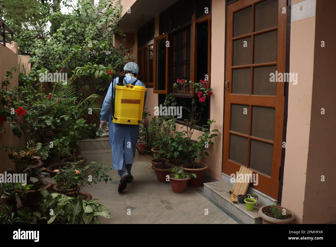 A professional worker in PPE uniform using sanitizing spray Stock Photo ...