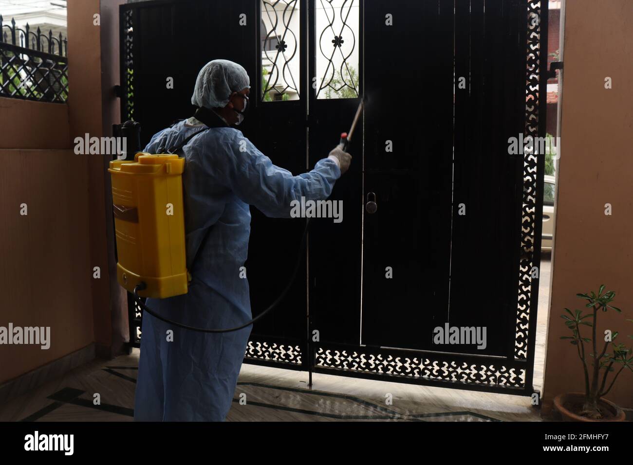 A professional worker in PPE uniform using sanitizing spray Stock Photo ...