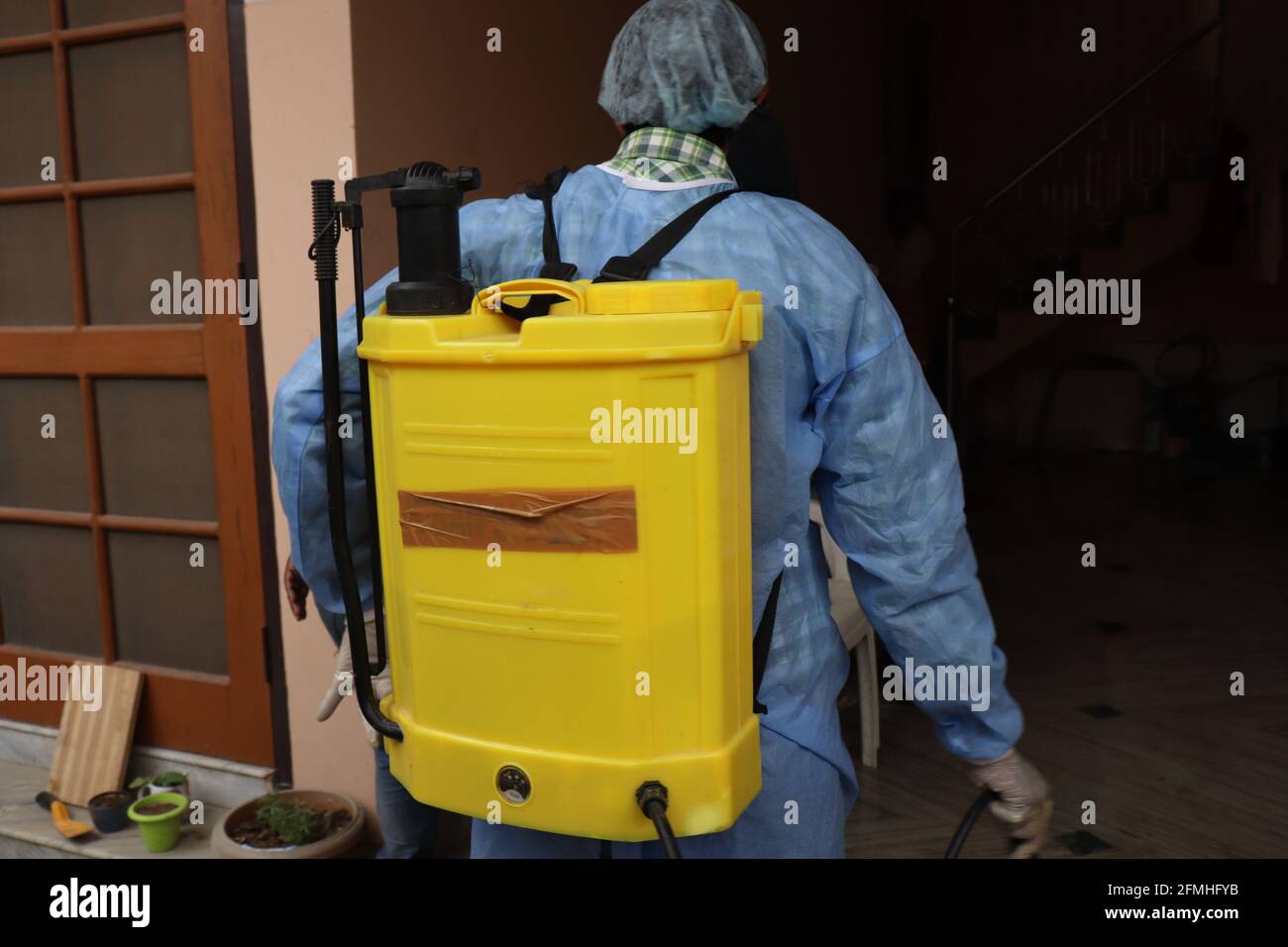A professional worker in PPE uniform using sanitizing spray Stock Photo ...