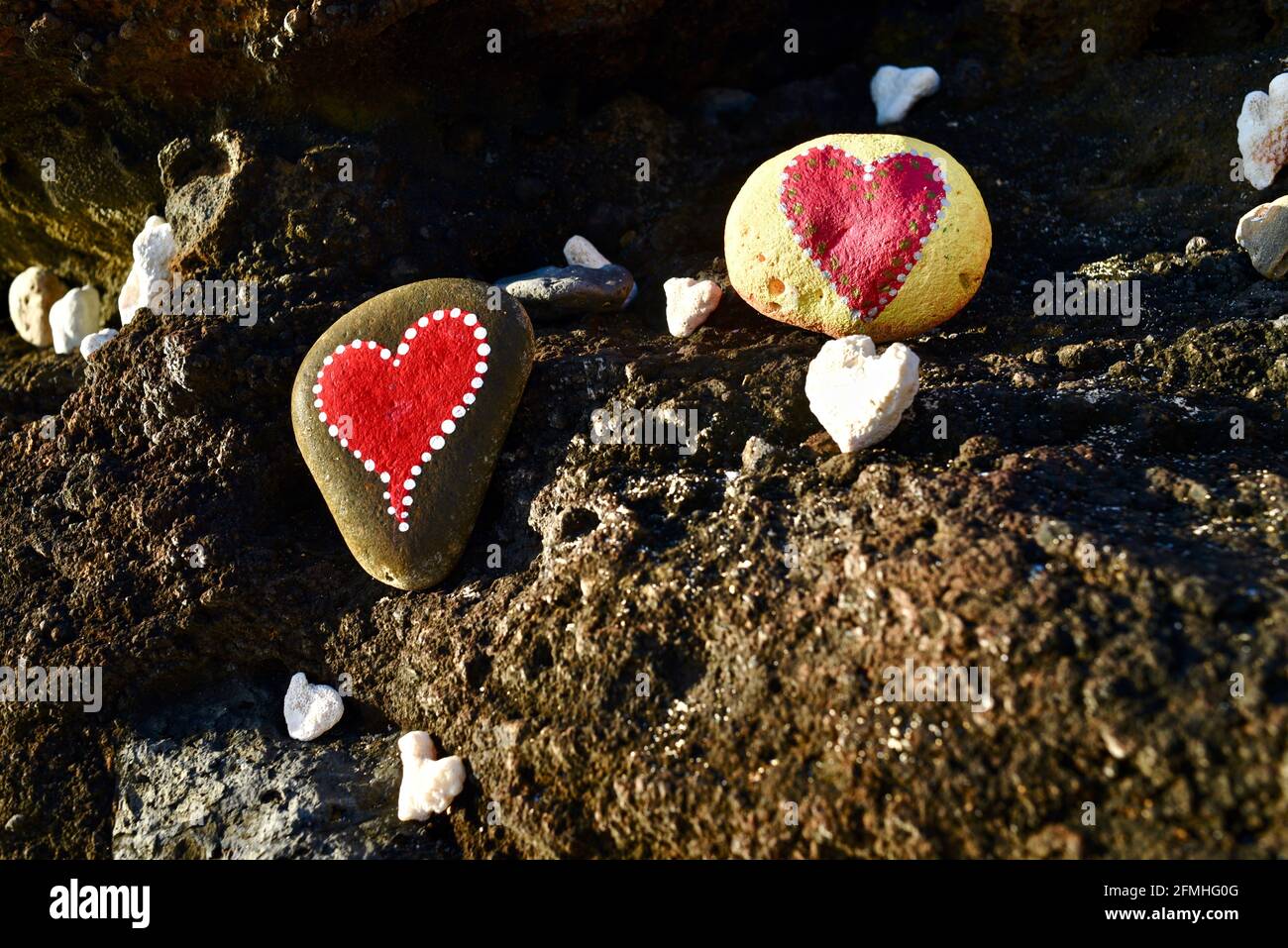 Heart shaped coral and stones, painted with bright red "love" hearts ...