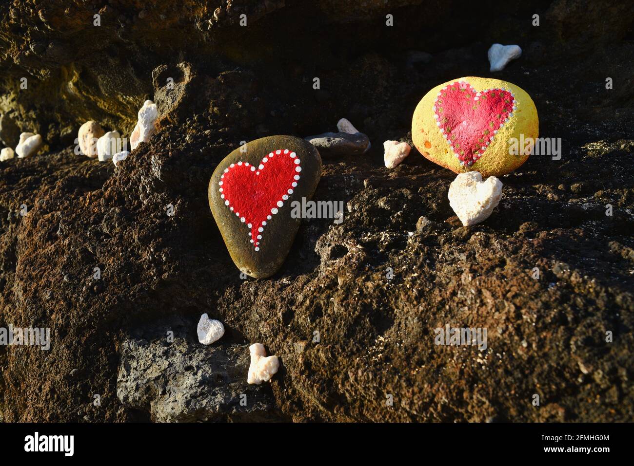 Heart shaped coral and stones, painted with bright red "love" hearts ...