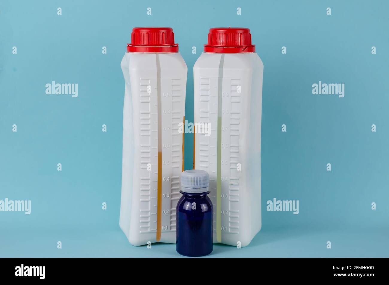 Liquid epoxy in bottles and blue dye on blue background. Two white ...