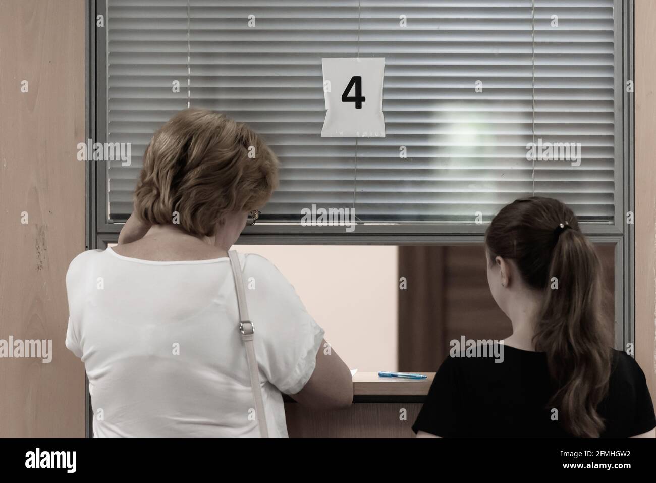 Reception of public services. A woman and a girl stand with their backs ...