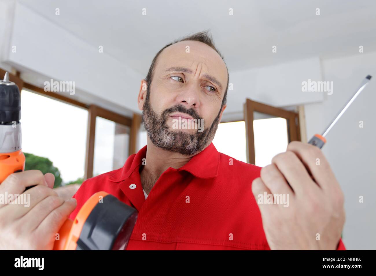 tradesman comparing traditional screwdriver to cordless power tool ...