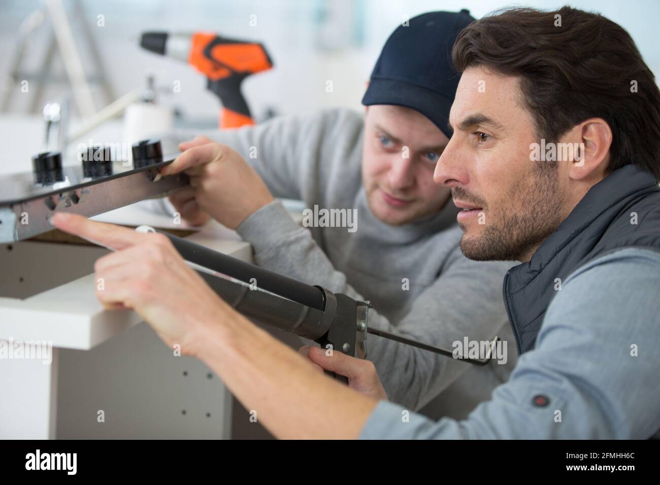 two men installing a new kitchen hob Stock Photo - Alamy