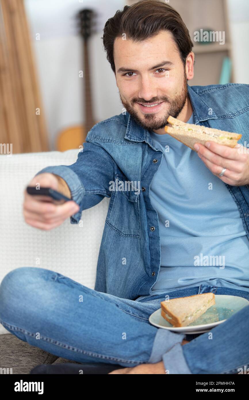 man changing tv channel while eating a sandwich Stock Photo - Alamy