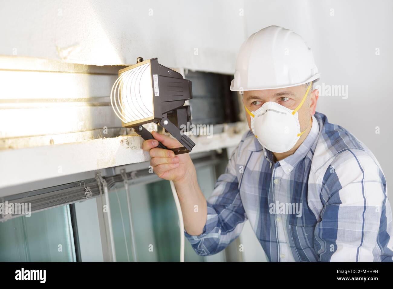 contractor using inspection light and wearing dust mask Stock Photo - Alamy