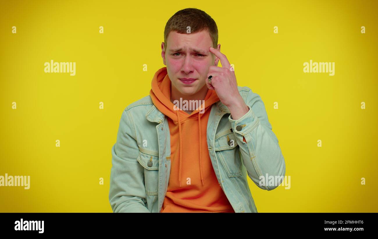 Teen man in jacket pointing at camera and showing stupid gesture ...