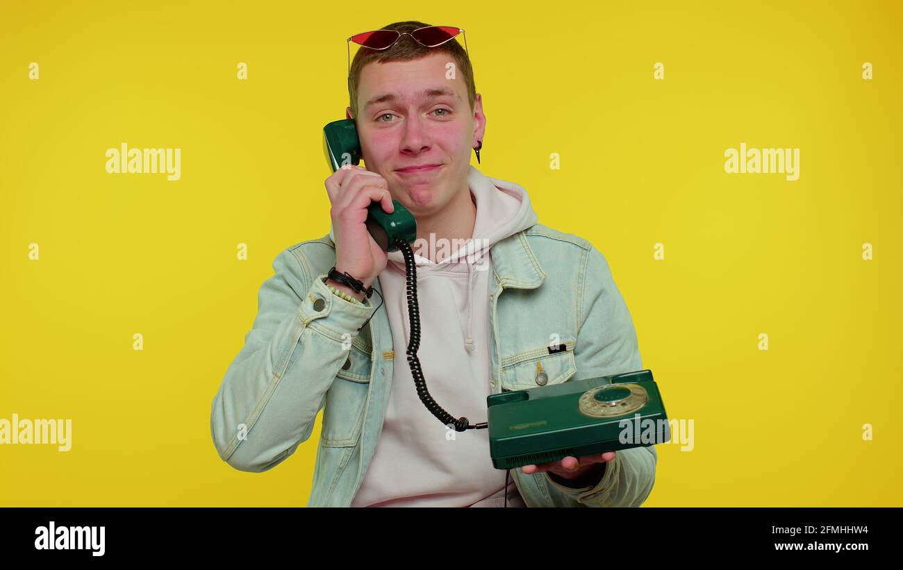 Cheerful teen man secretary talking on wired vintage telephone of 80s ...