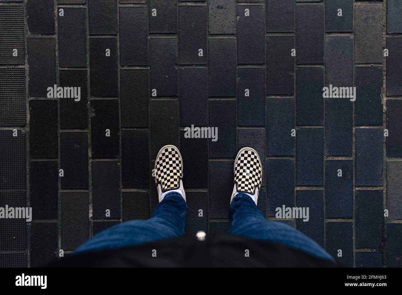 A top view of black and white checkered shoes on a pavement surface ...