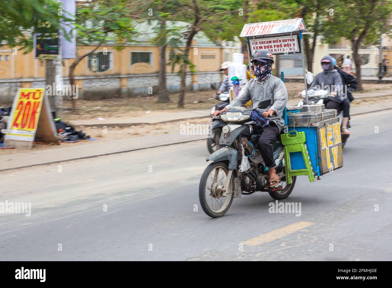 Vietnamese motorcycle in motion carrying heavily loaded food cart on ...