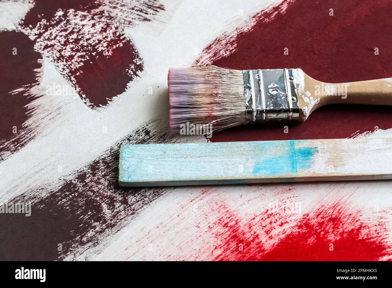 Closeup of a used dirty paintbrush on a paper with red-colored paint ...