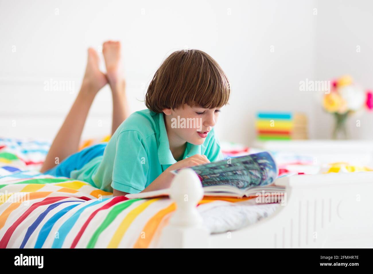 Child reading book in bed in white sunny bedroom with window. Kids read ...