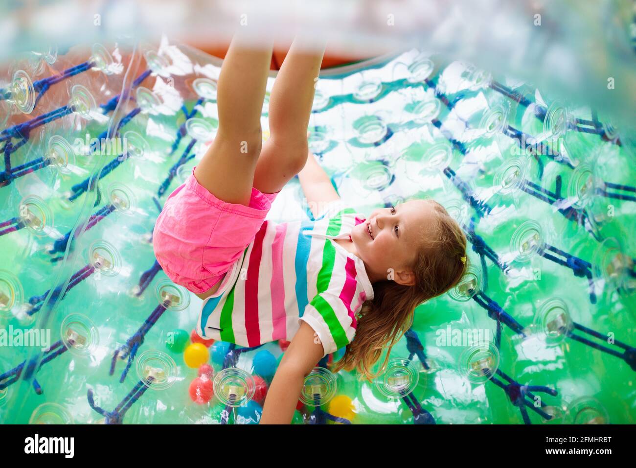 Child in roller wheel jumping on colorful playground trampoline. Kids ...