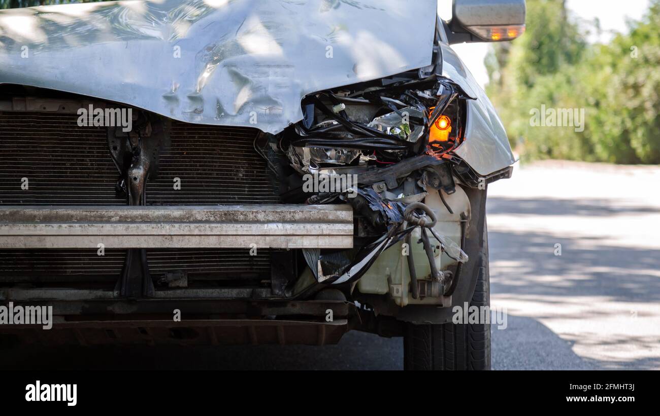 Destroyed car in car crash traffic accident on city road on city road. Smashed broken front auto ...