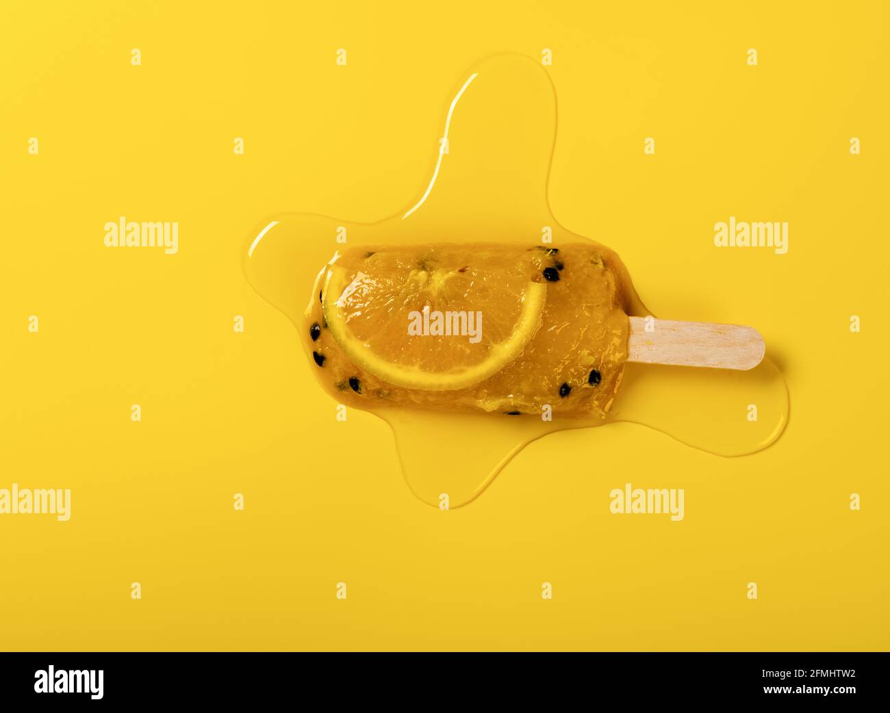 half melted passion fruit flavor popsicle with slice of orange on a ...