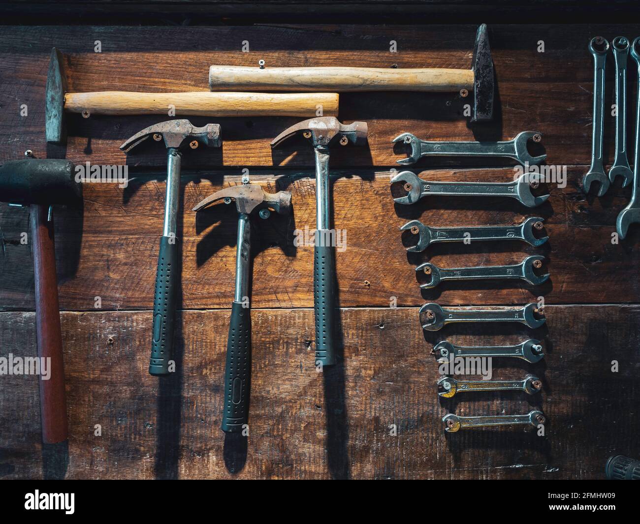 Set of wrench and old hammers hanging on wooden wall background ...