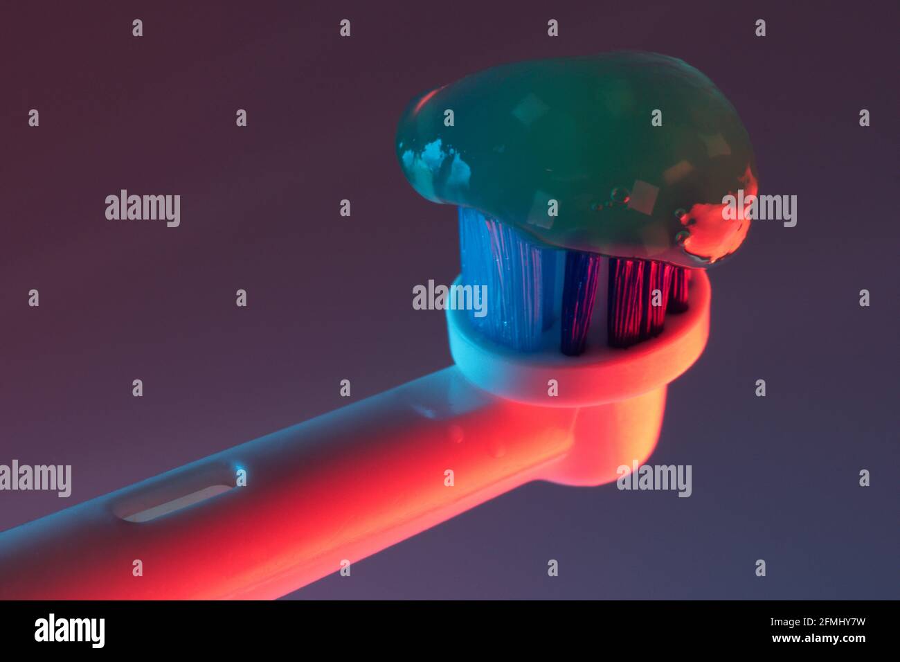 Artistic picture of toothbrush head with green toothpaste being lit by ...