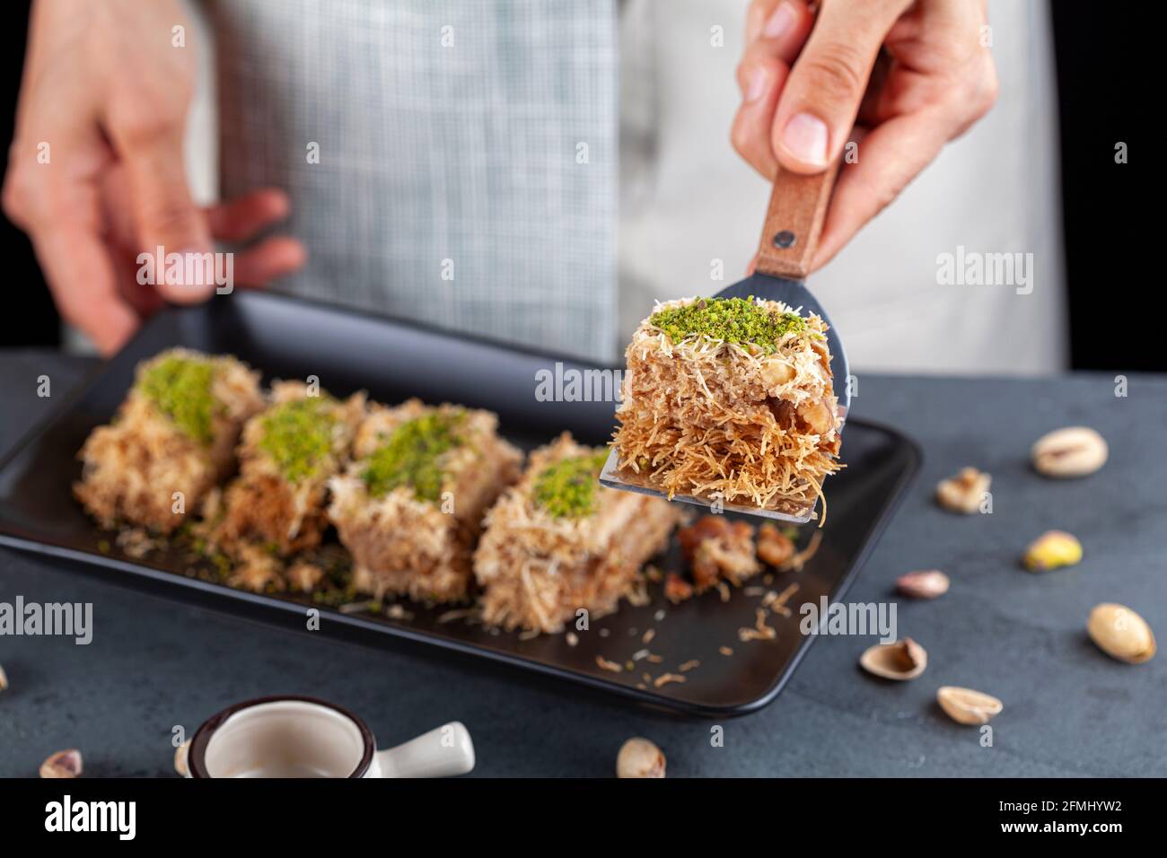 A Turkish woman is serving a slice of delicious traditional kadayif ...