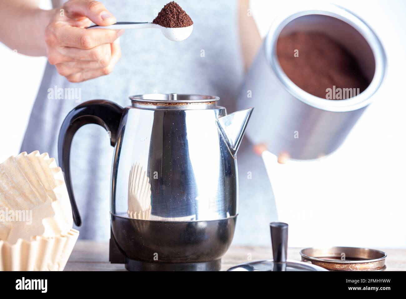 A caucasian woman is taking a teaspoon of ground coffee from a jar ...