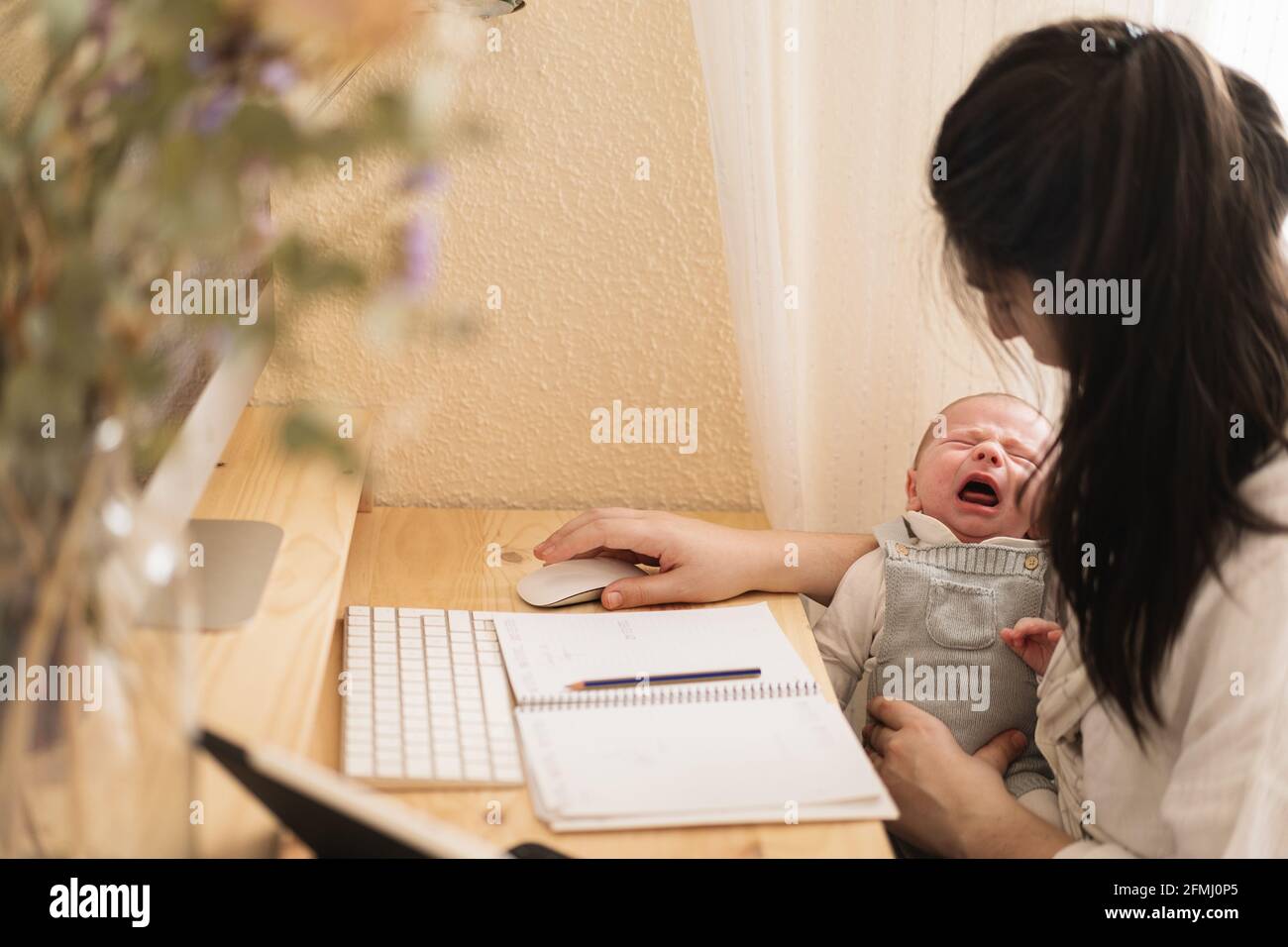 Mom with upset little child sitting at table with copybook and desktop ...