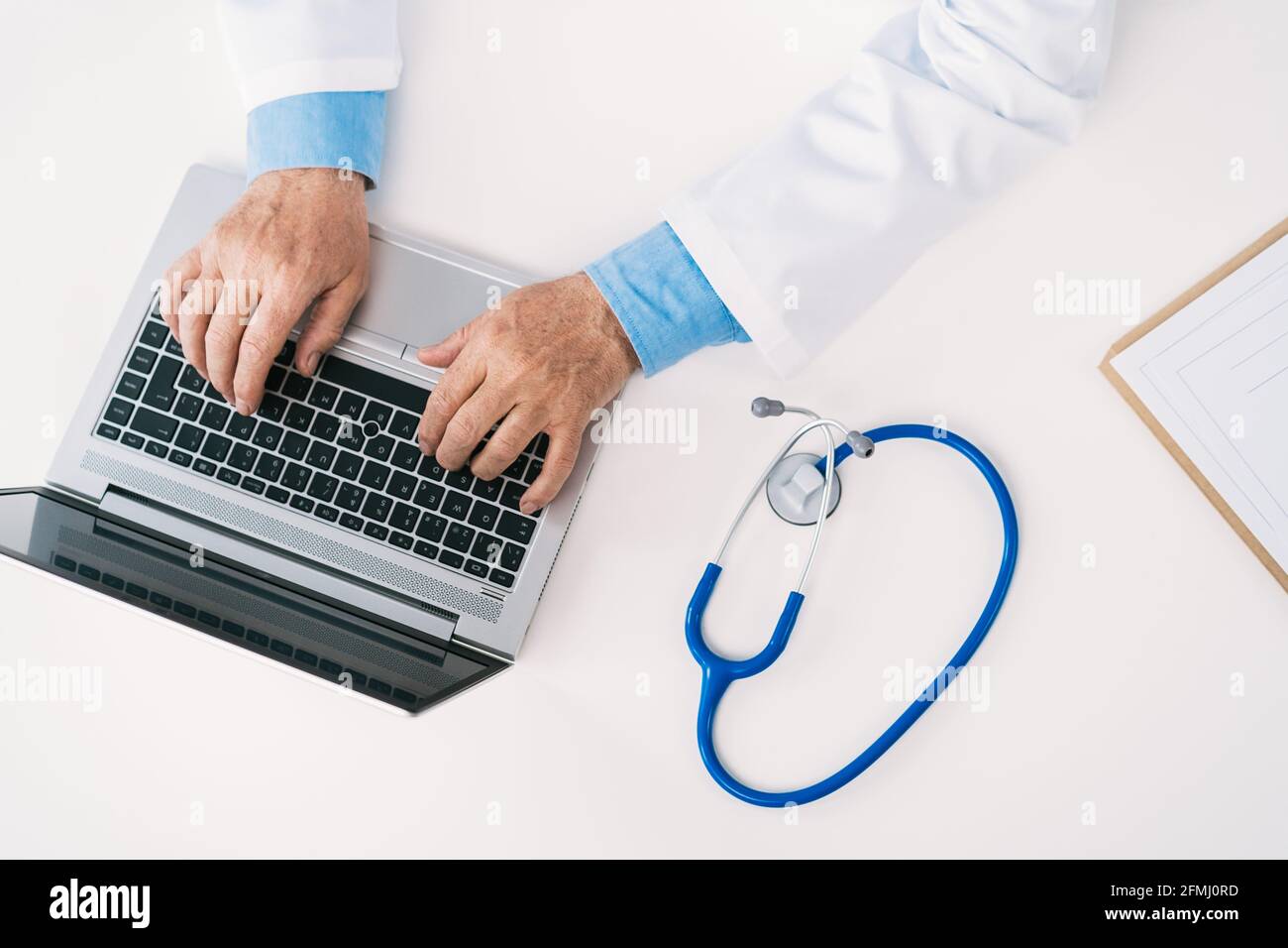 From above cropped unrecognizable male doctor in uniform typing on ...