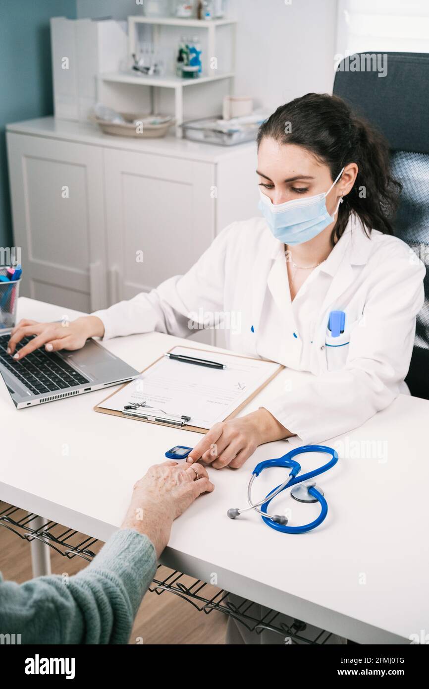 Young female doctor with laptop checking up heartbeat of crop anonymous ...