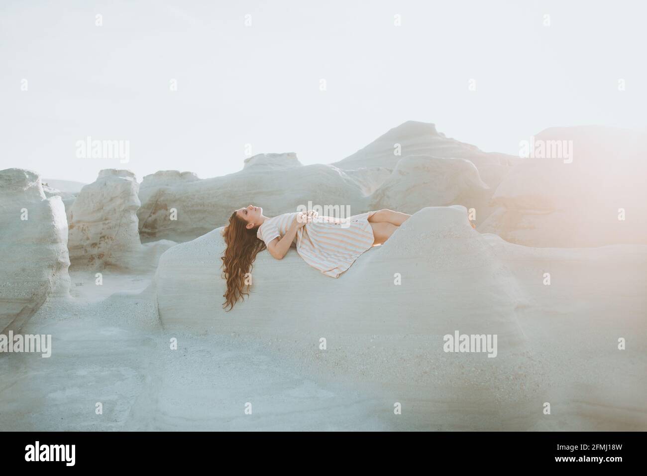 Side view attractive young female in white sundress lying on rough ...