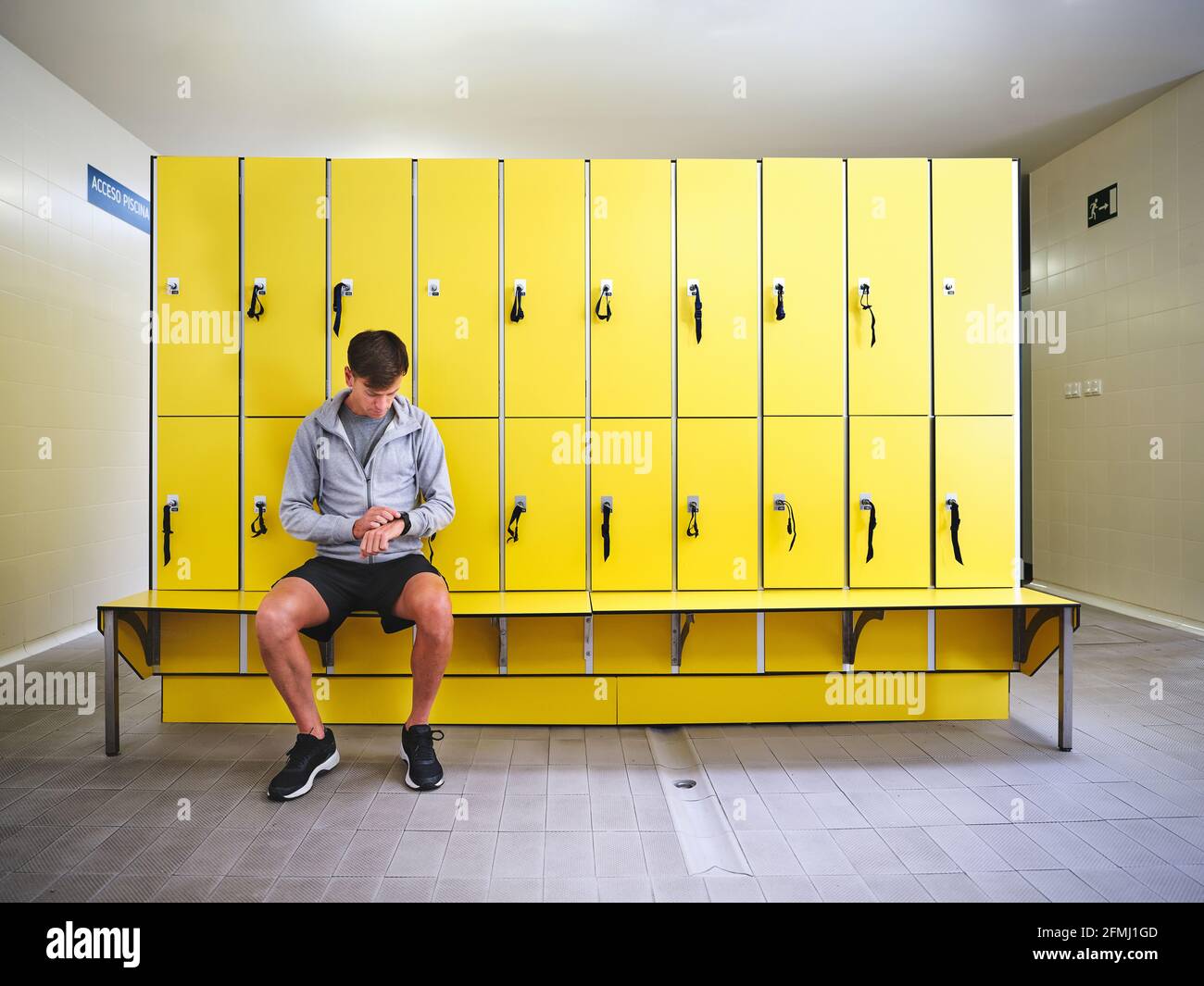 Adult male athlete in sports clothes checking up time while sitting on ...