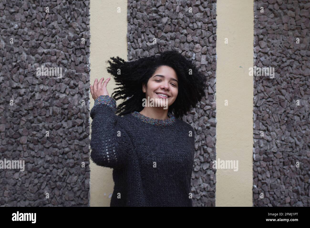 Delighted ethnic female with Afro hairstyle standing on street and ...