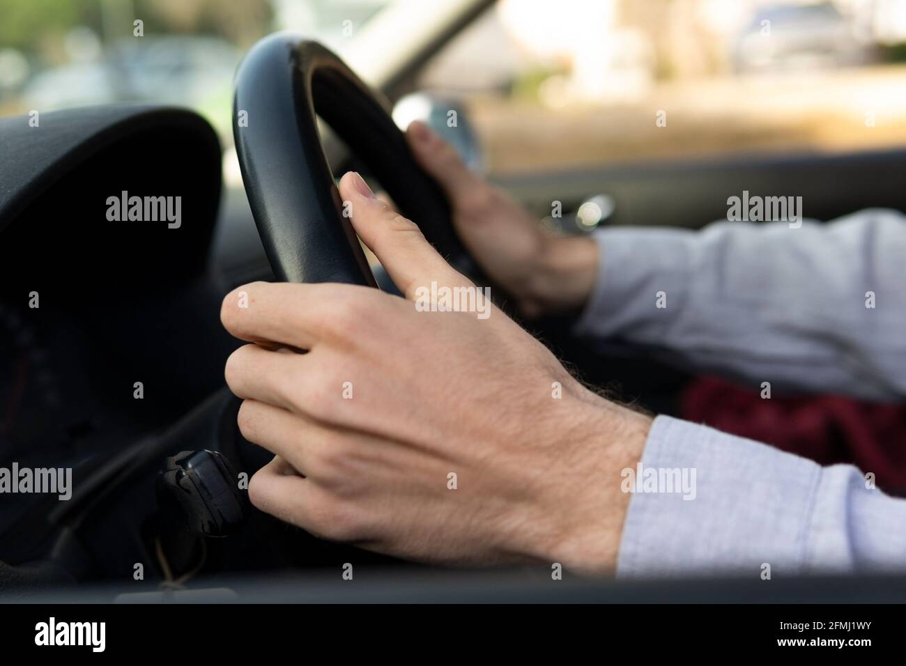 Side view of crop faceless male with hands on steering wheel driving ...