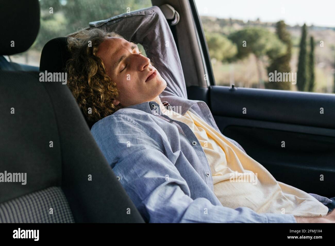 Relaxed young male traveler sleeping on driver seat of modern ...