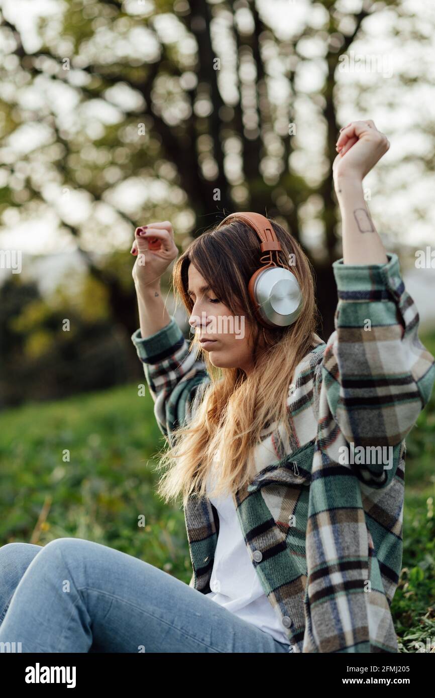 Side view of female listening to music from headphones while having fun ...