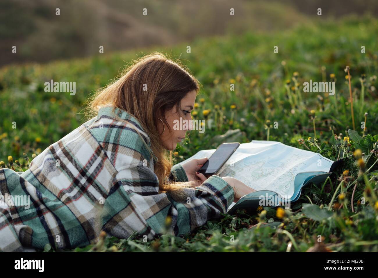 Side view of young female tourist with cellphone watching route map ...
