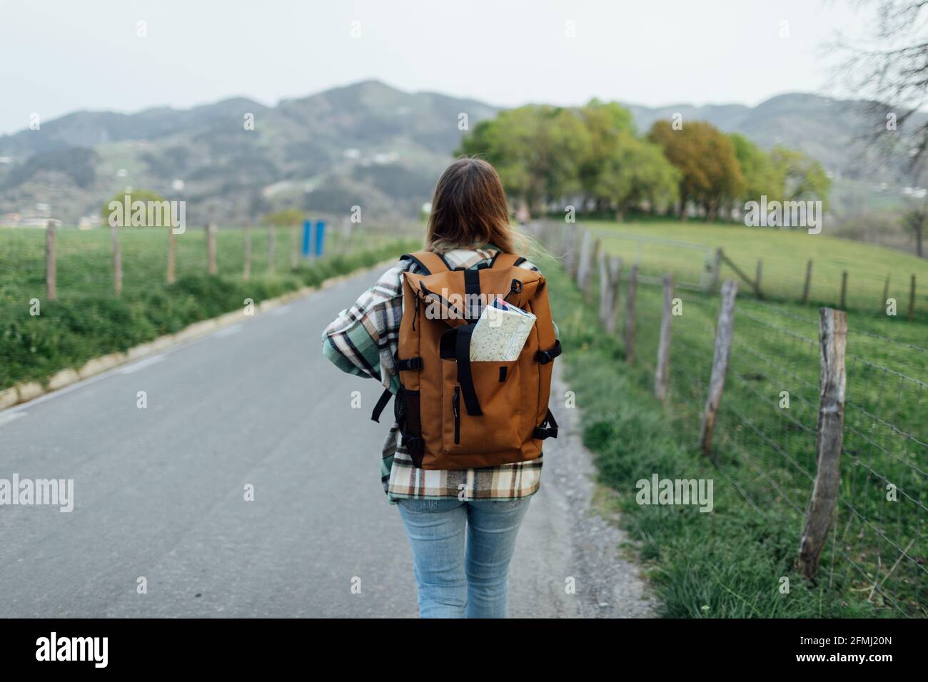 Back view of anonymous female hiker with route map in rucksack ...