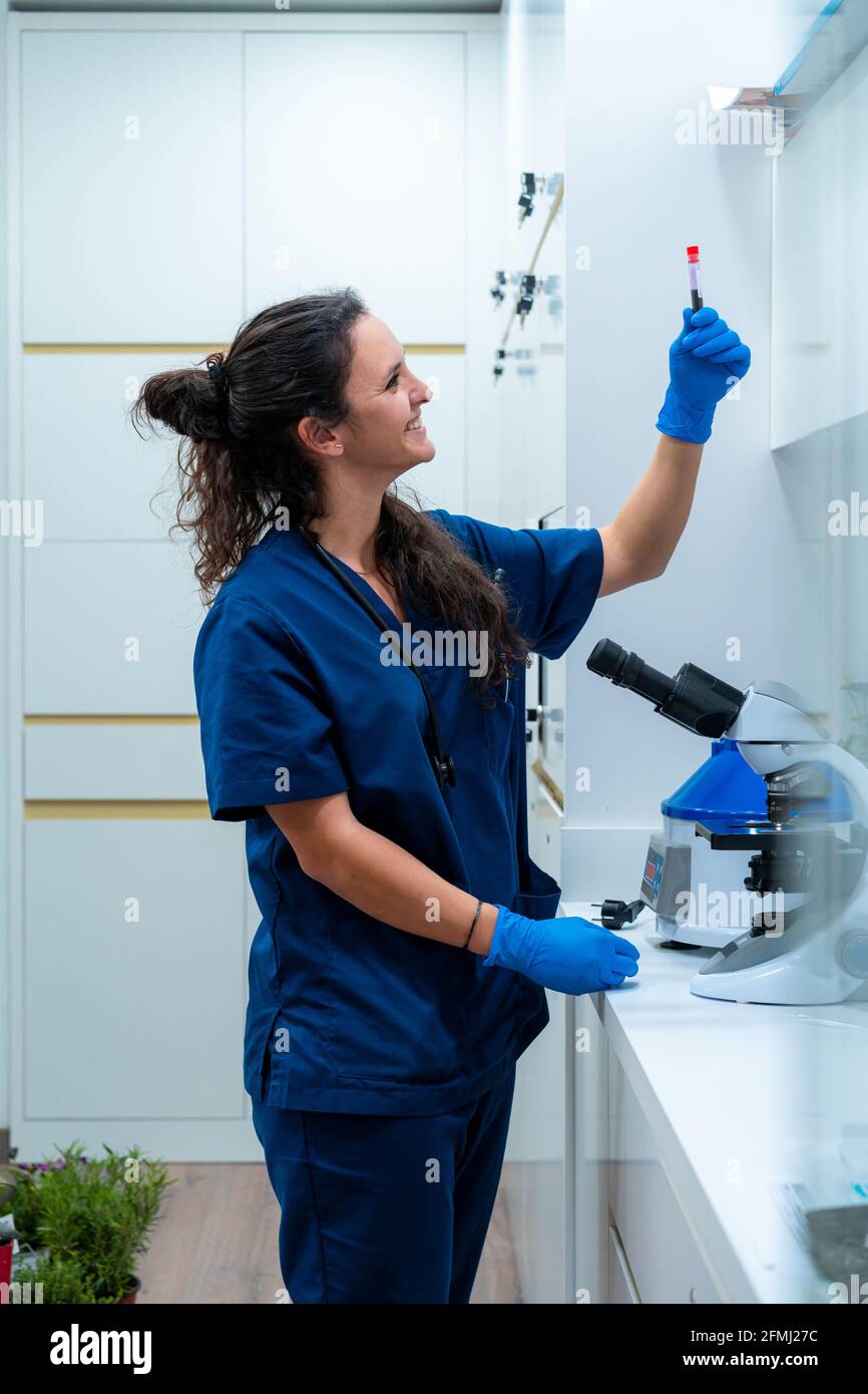 Side view of content female veterinarian in uniform with test tube ...