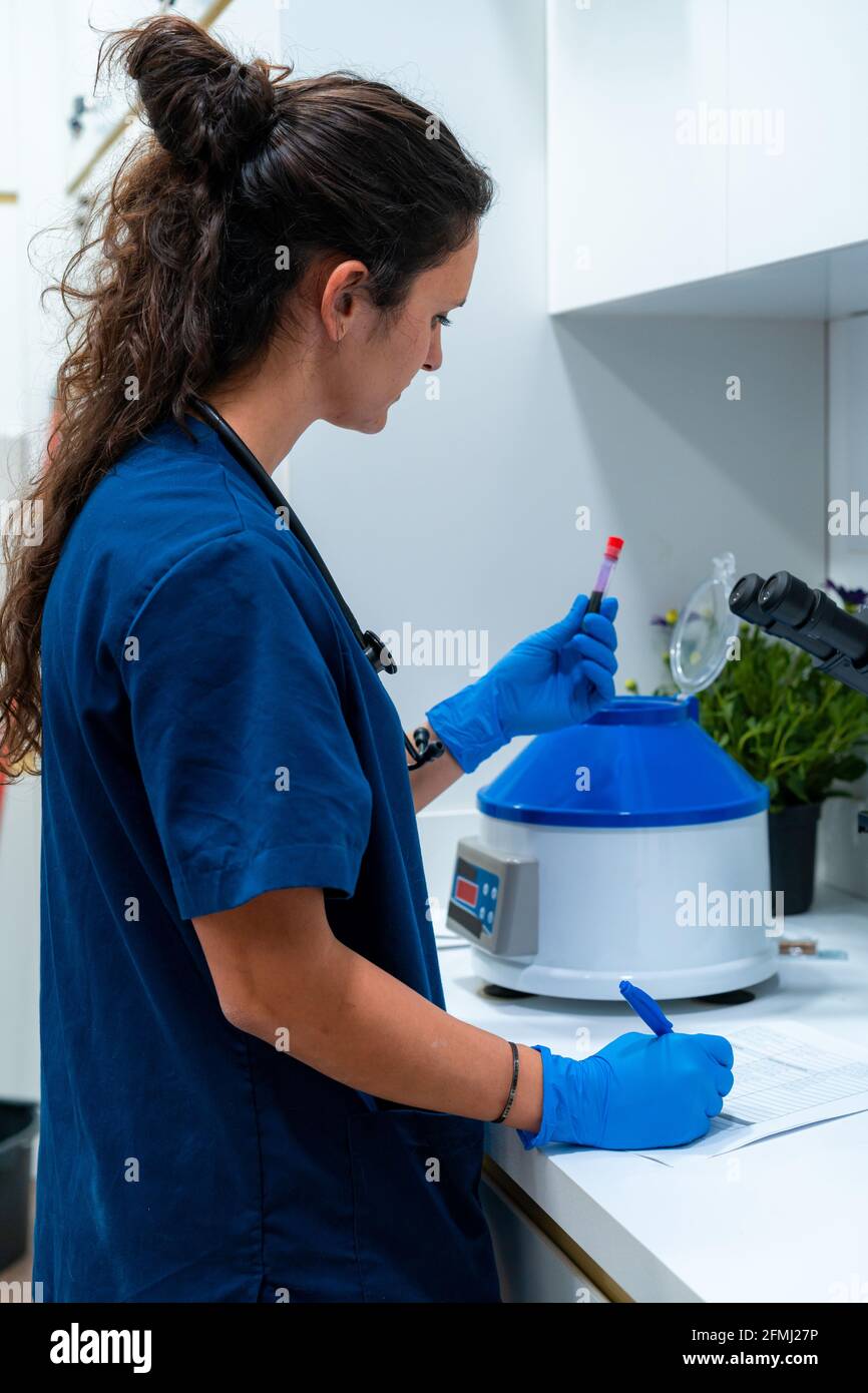 Side view of content female veterinarian in uniform with test tube ...