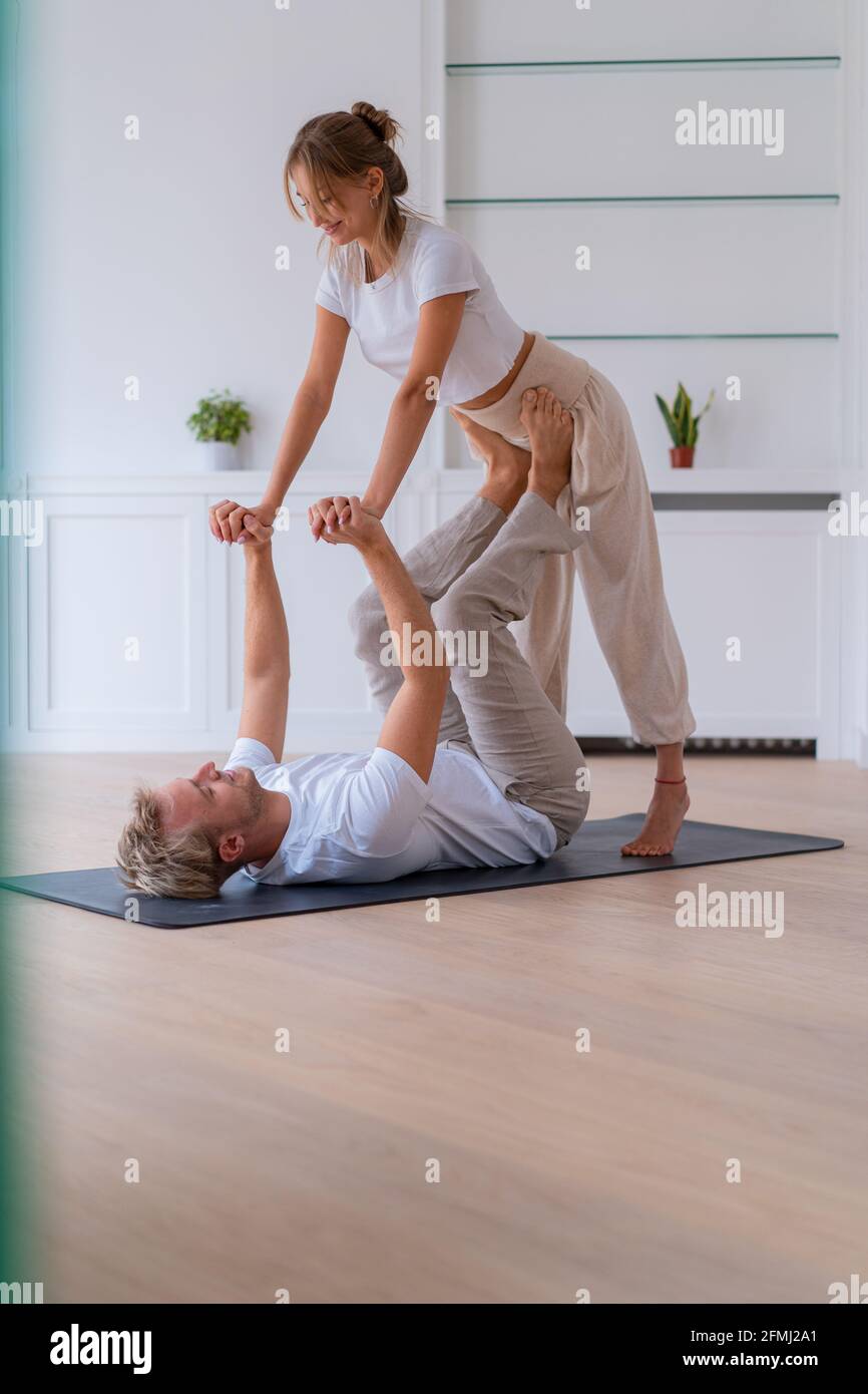 Side view of boyfriend lifting girlfriend while doing acro yoga ...