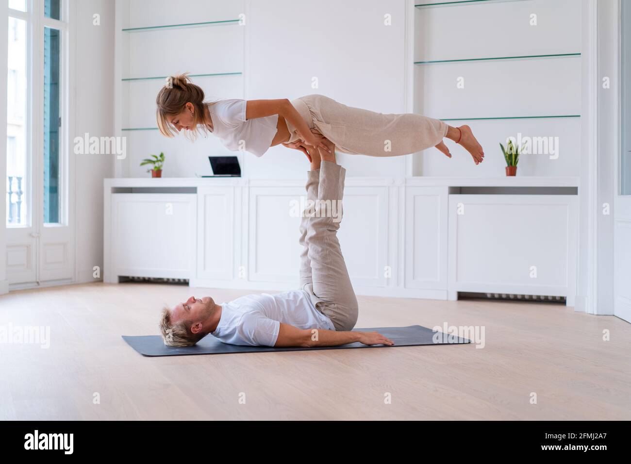 Side view of boyfriend lifting girlfriend while doing acro yoga ...