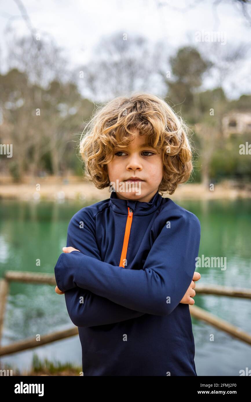 Lonely child in blue clothes with folded arms looking away against ...