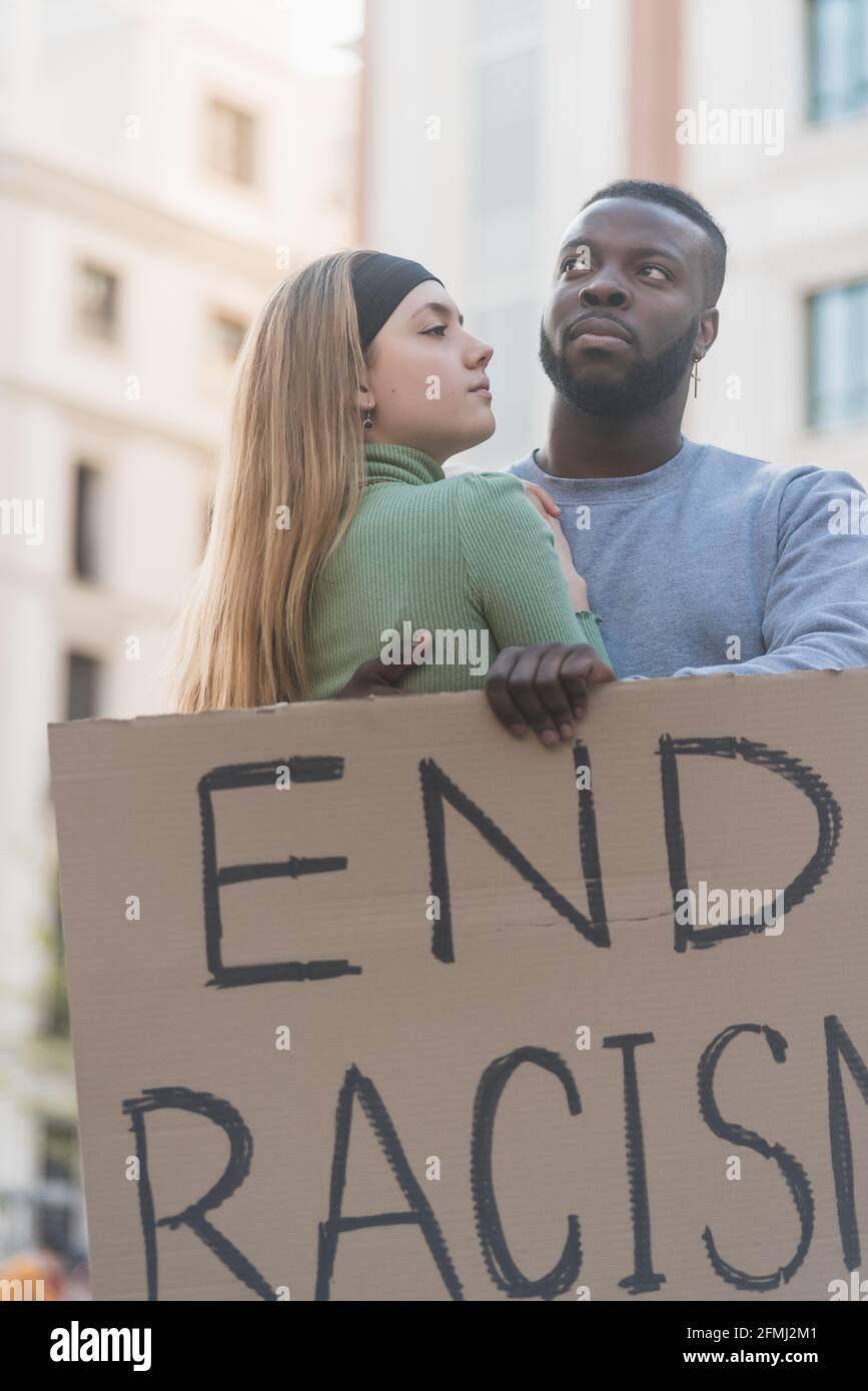 Multiracial couple embracing in city street while protesting with End ...