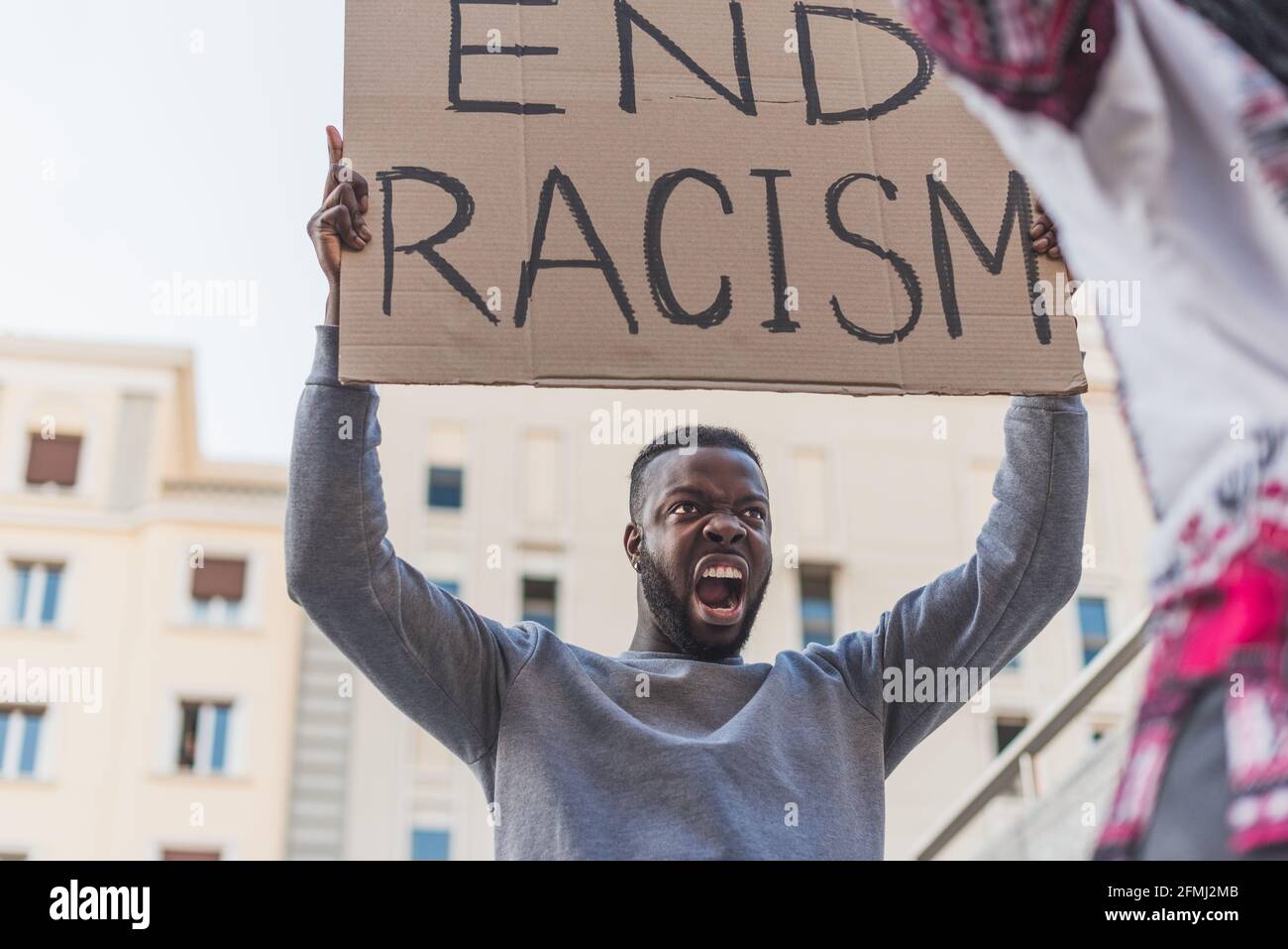 Low angle of African American male activist with End Racism poster ...