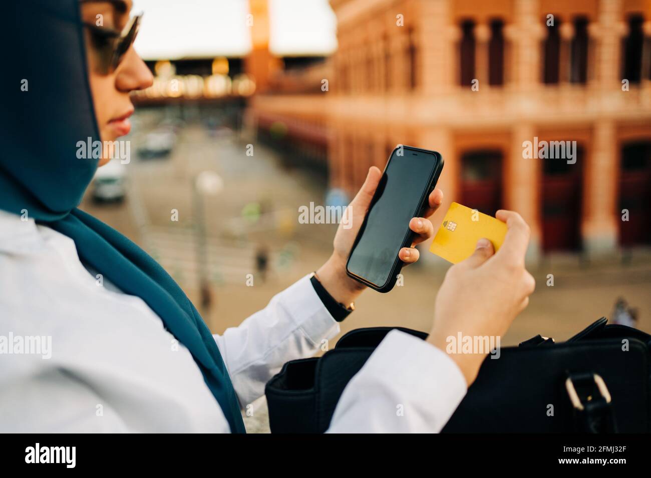 Side view of crop stylish Muslim female paying with plastic card for ...
