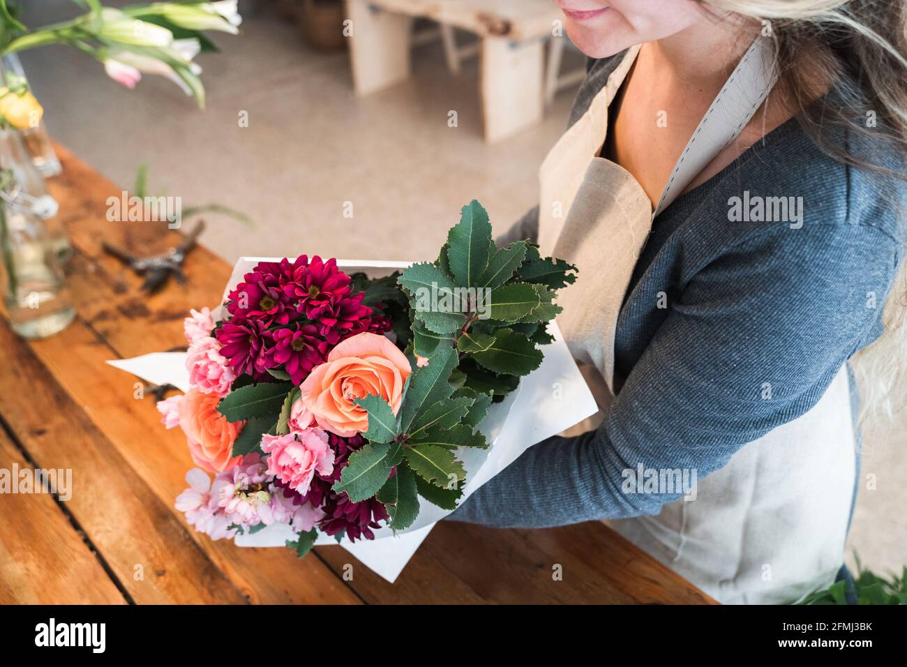 Crop unrecognizable young female florist with long wavy hair in casual ...