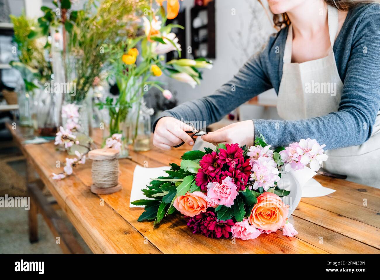 Crop unrecognizable young female florist with long wavy hair in casual ...