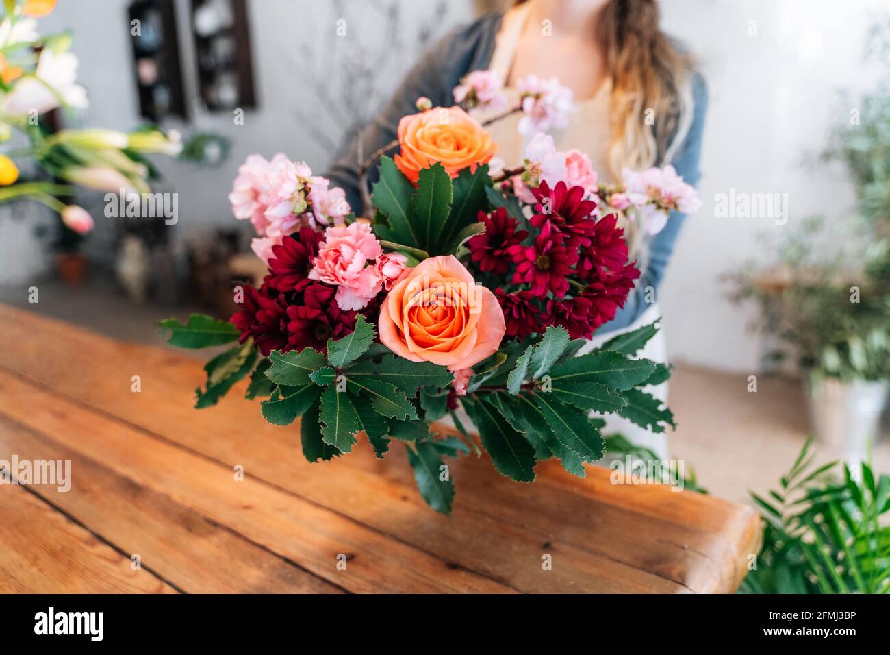 Crop unrecognizable young female florist with long wavy hair in casual ...