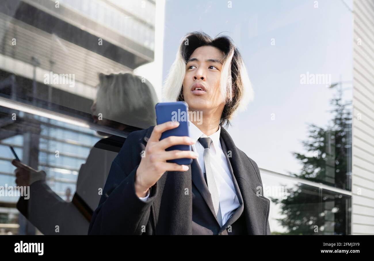 Young Asian male executive in formal apparel text messaging on mobile ...