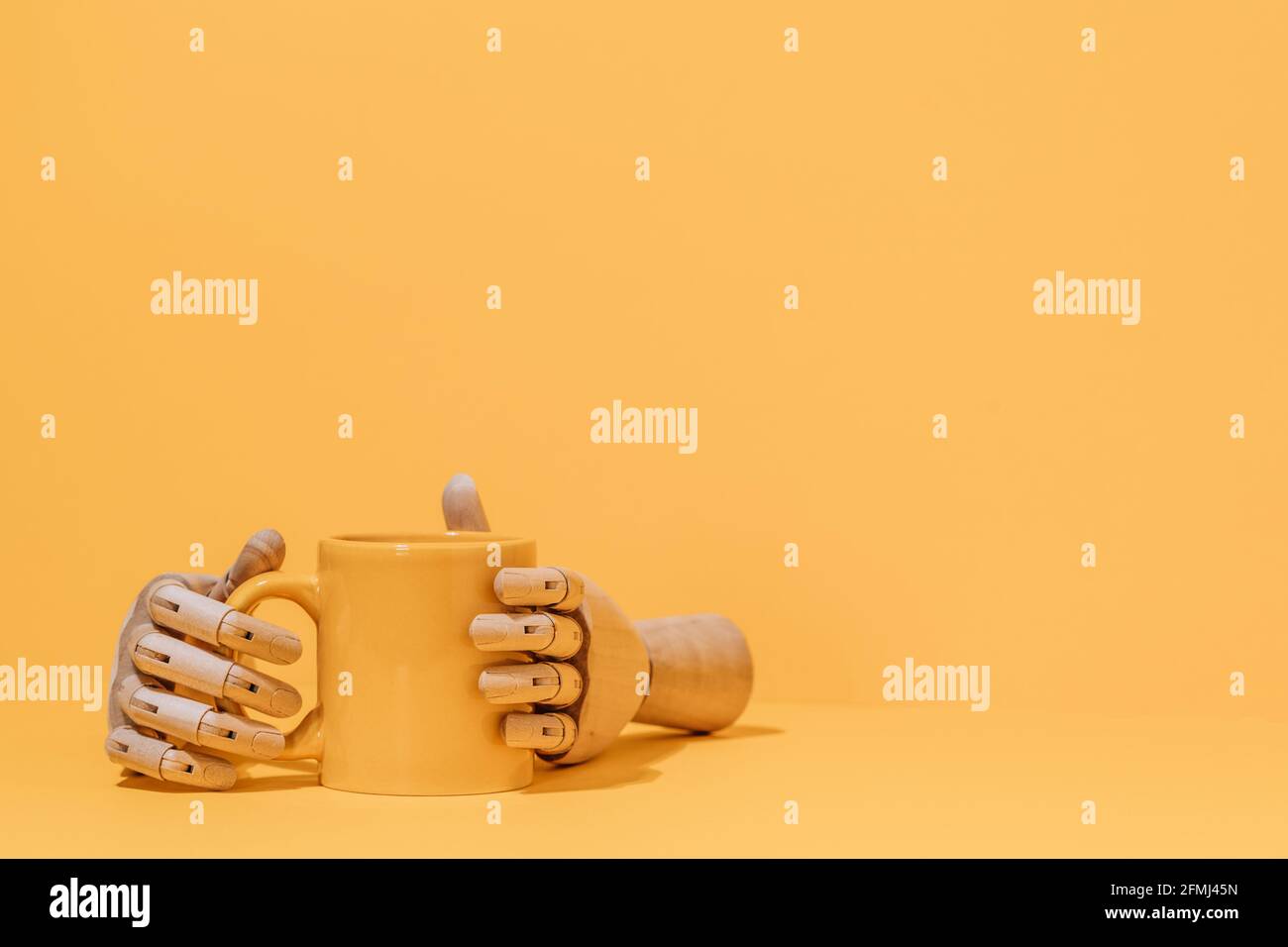 Creative ornamental wooden hand holding colorful mug on yellow ...